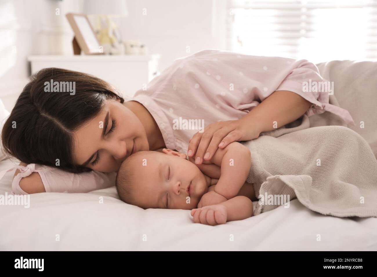 Young mother resting near her sleeping baby on bed at home Stock Photo ...