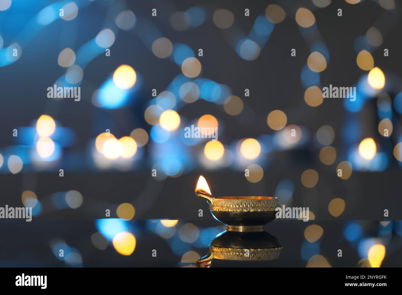 Lit diya on table against blurred lights, space for text. Diwali lamp ...