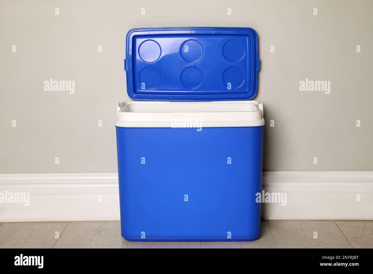 Open blue plastic cool box near light grey wall indoors Stock Photo - Alamy