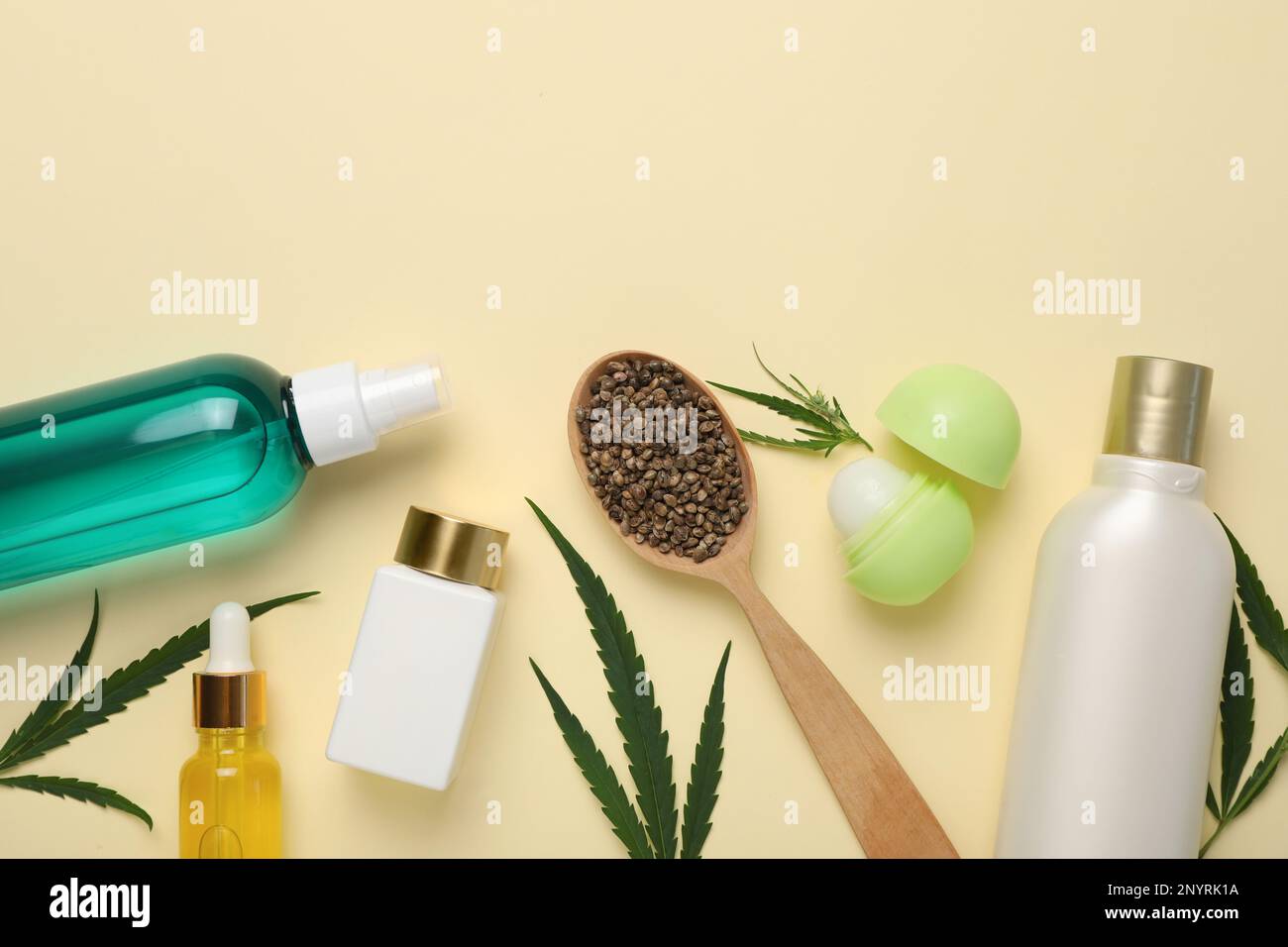 Different hemp cosmetics, green leaves and seeds on beige background ...