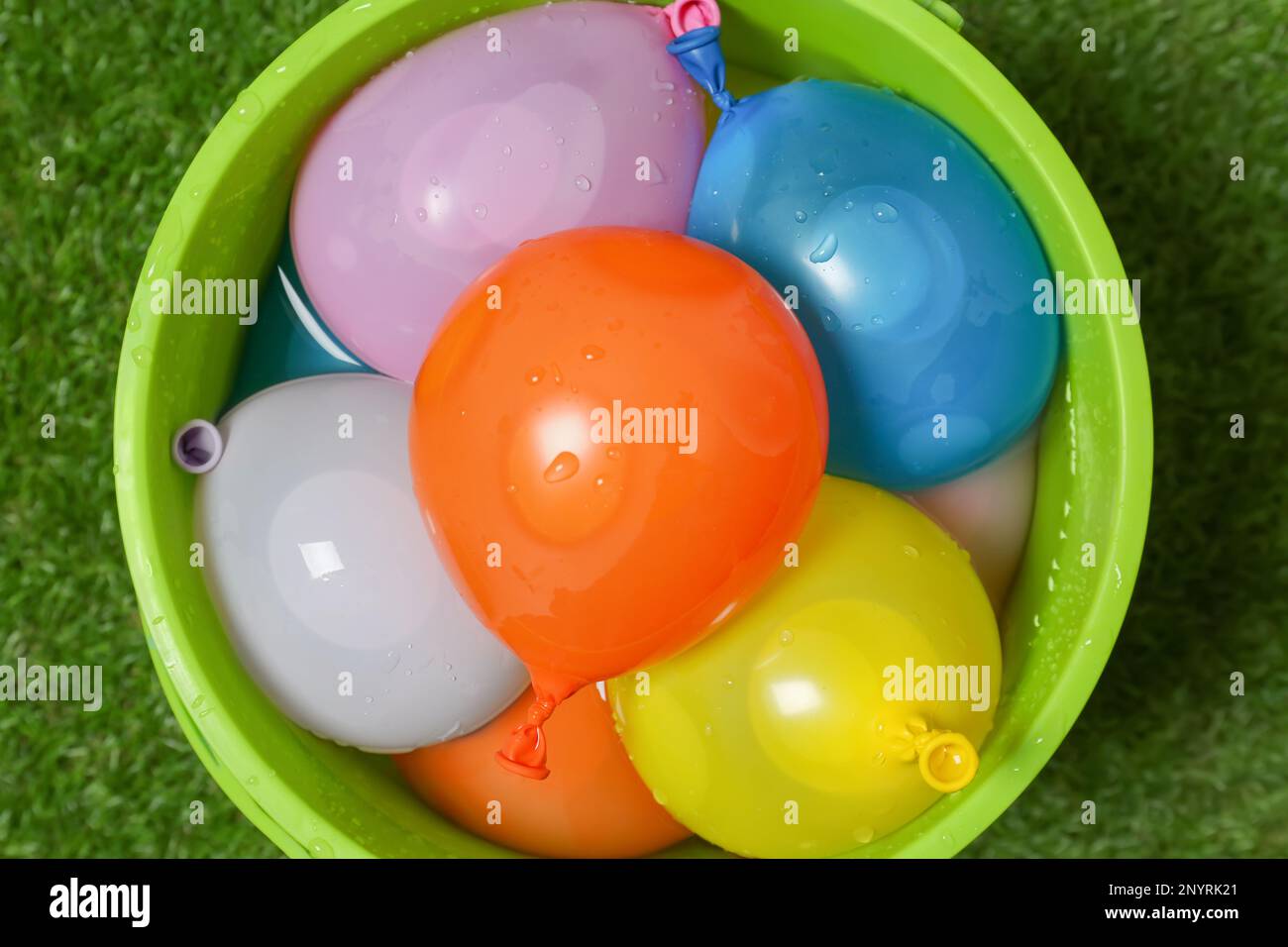 Bucket full of colorful water bombs on green grass, top view Stock ...