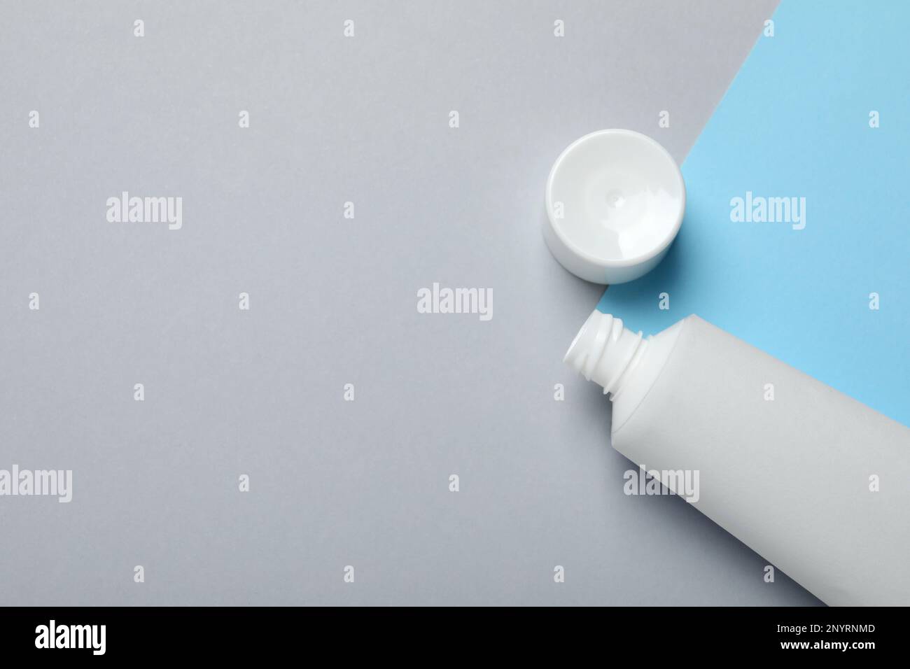 Blank tube of toothpaste and lid on color background, flat lay. Space ...