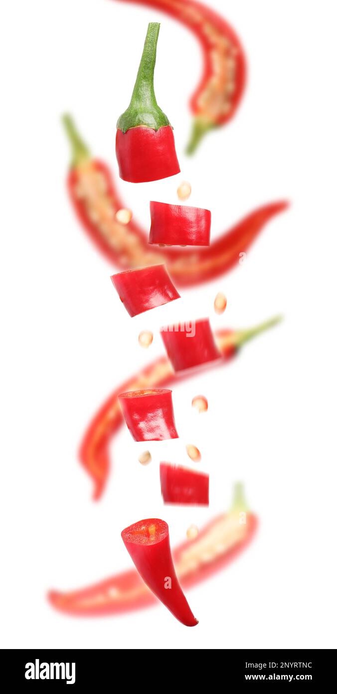 Pieces of ripe red chili peppers falling on white background. Vertical ...