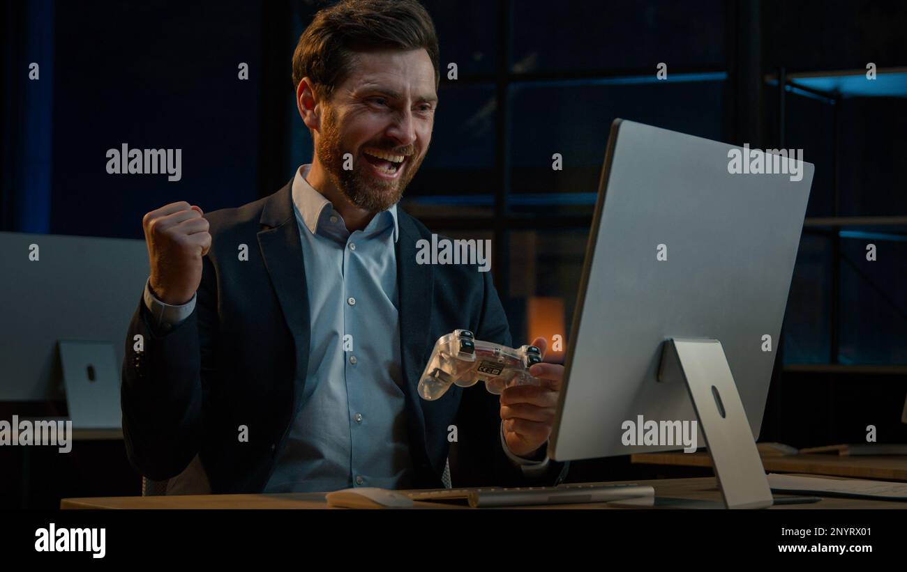 Adult businessman employee working in evening office happy male gamer ...