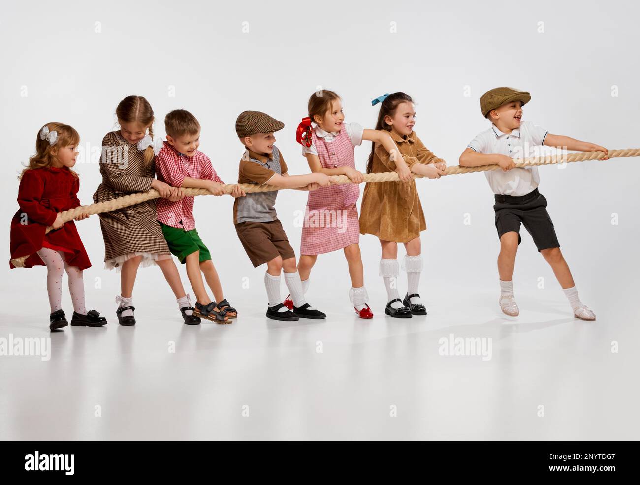 Group of little children, boys and girls playing together, pulling rope ...