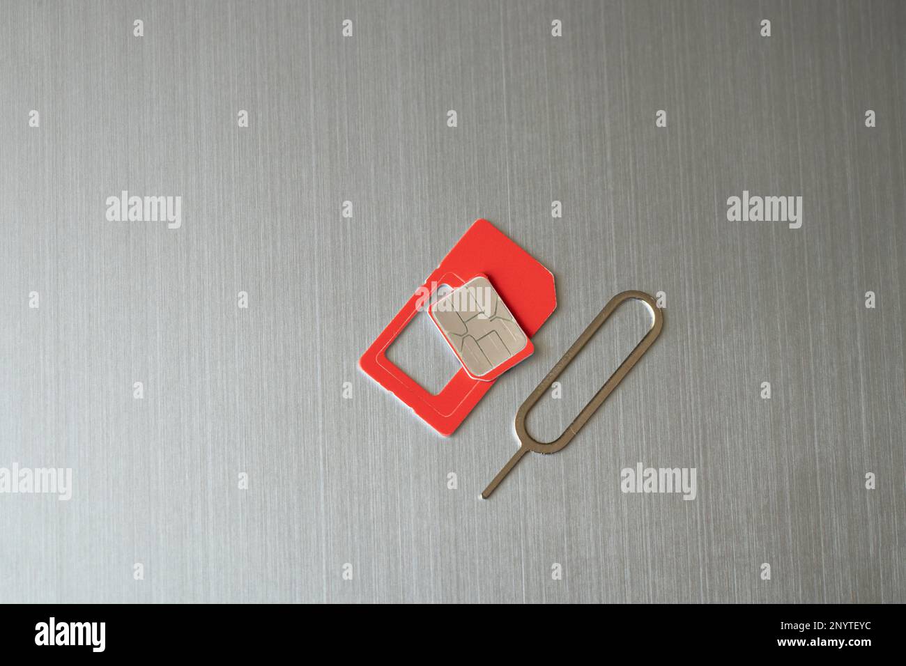 a sim card and a paper clip for opening a slot for a sim card lies on a ...
