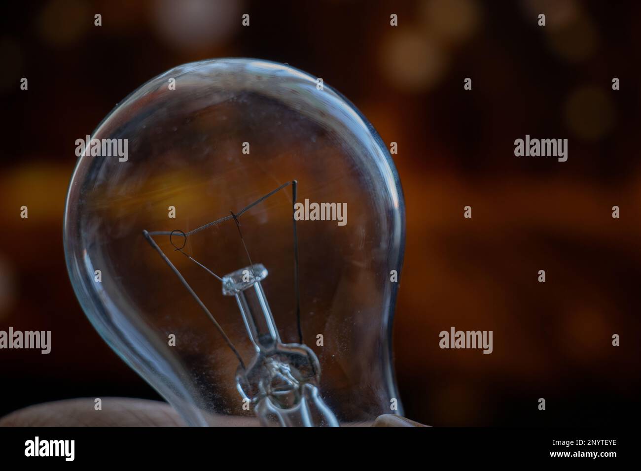 old incandescent light bulb in hand on blurry dark background Stock ...
