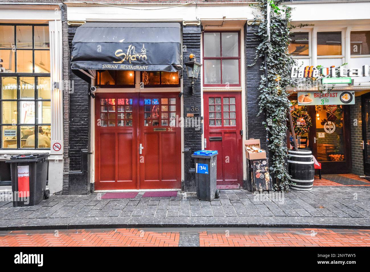a brick building with a red door and black aws on the side of the street in front of it Stock ...