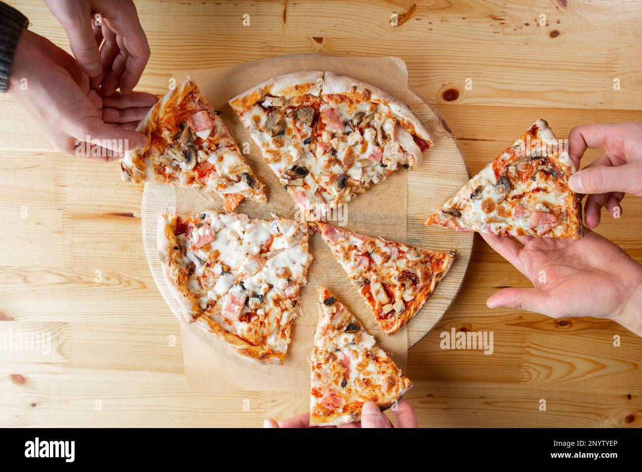 three people taking slices of pizza out of the box. fast delivery of ...