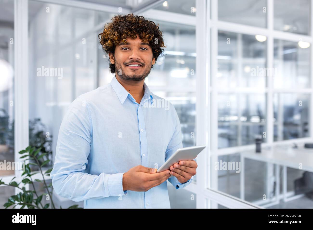 Portrait of young programmer with tablet computer inside office ...