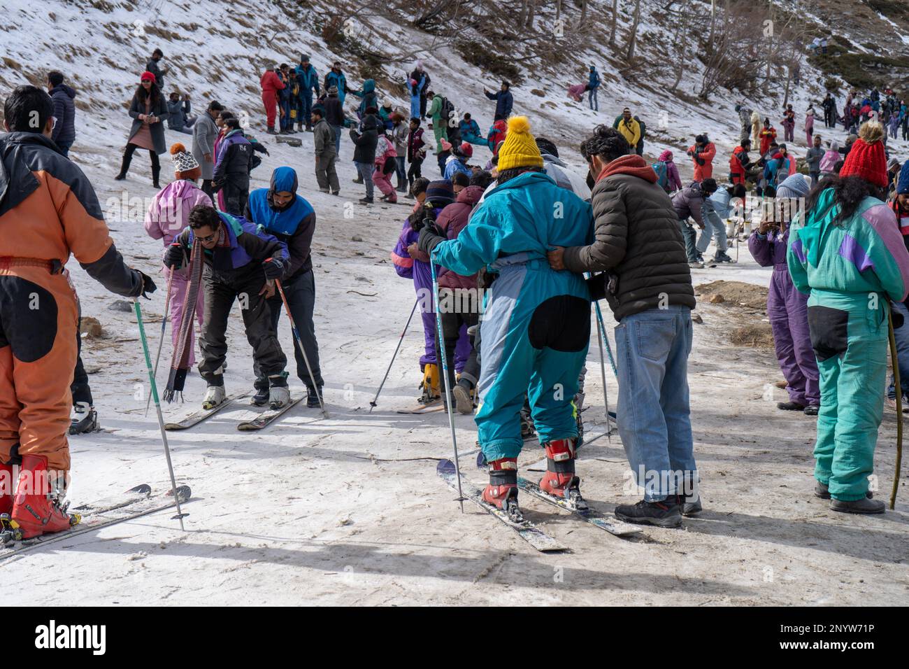Panning shot of crowd of people in winter wear playing in snow, sking ...