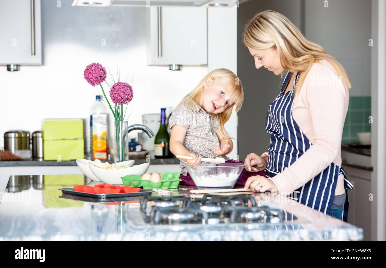 Family Life, Making Cakes. A mother showing her young daughter how to ...