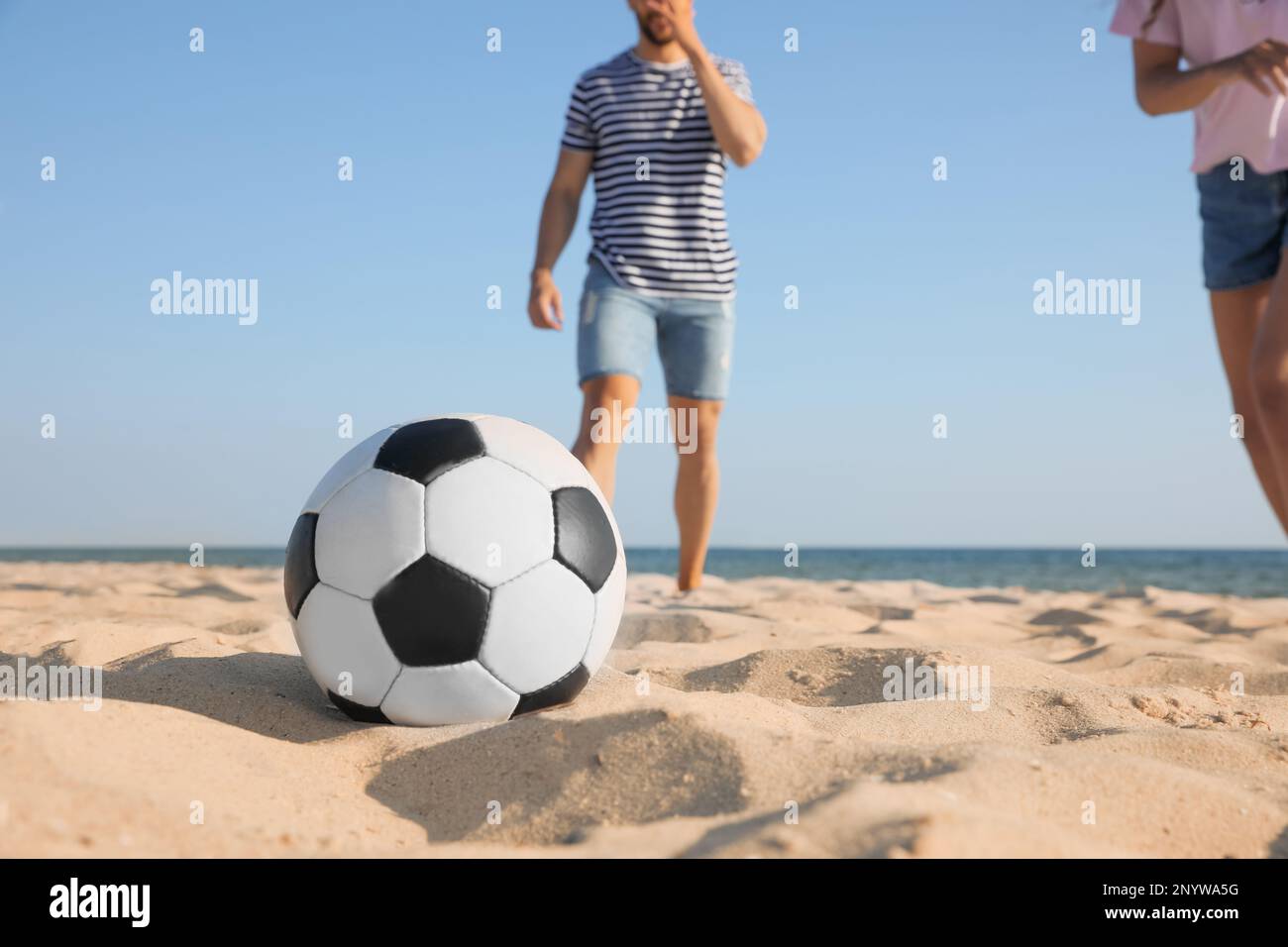 Friends playing football at beach, focus on ball Stock Photo - Alamy