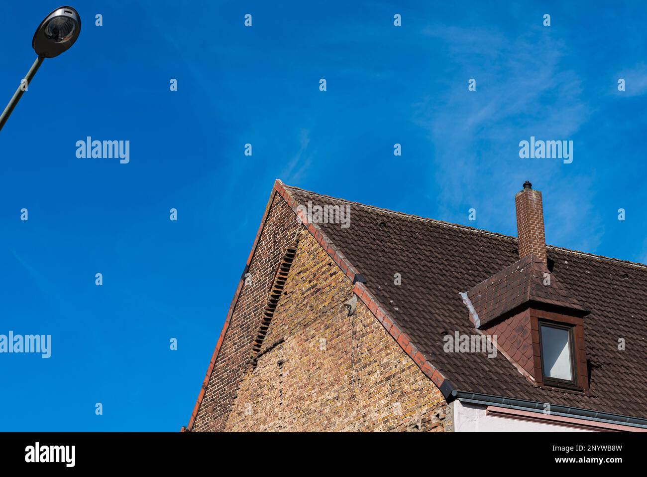 Part of a tiled roof with a dormer window and chimney. Street lamp ...