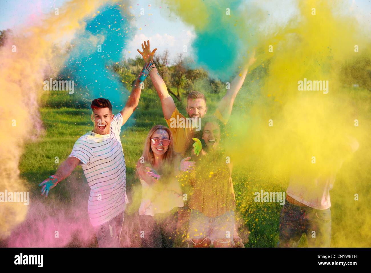 Happy friends having fun with colorful powder dyes outdoors. Holi ...