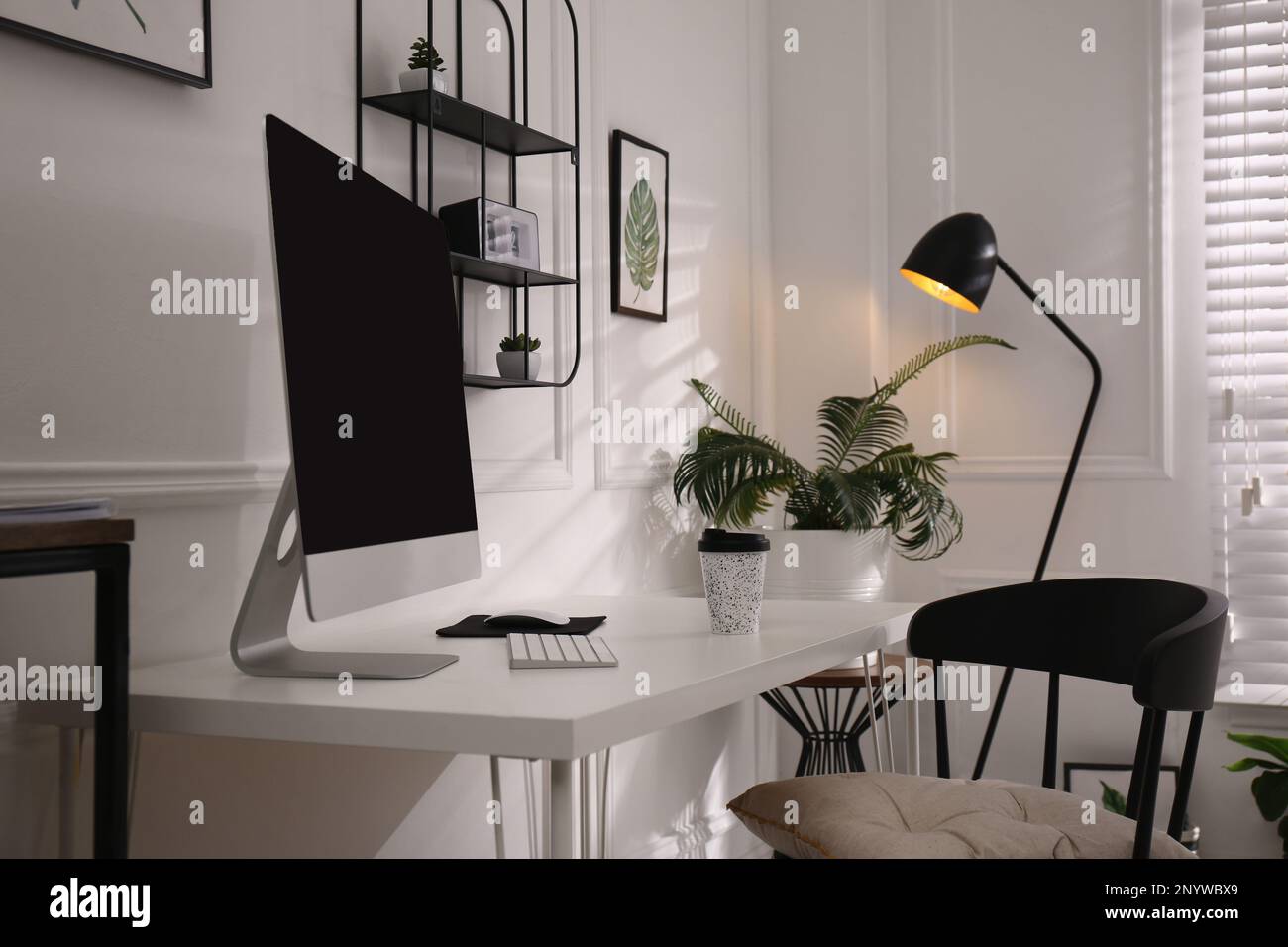 Comfortable workplace with modern computer and houseplants in room ...