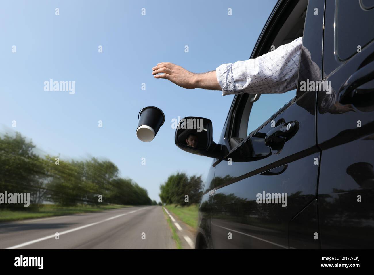 Driver throwing away paper coffee cup from car window. Garbage on road ...