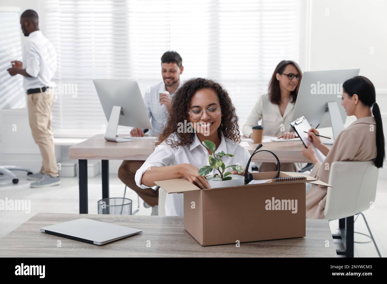 New coworker unpacking box with personal items at workplace in office ...
