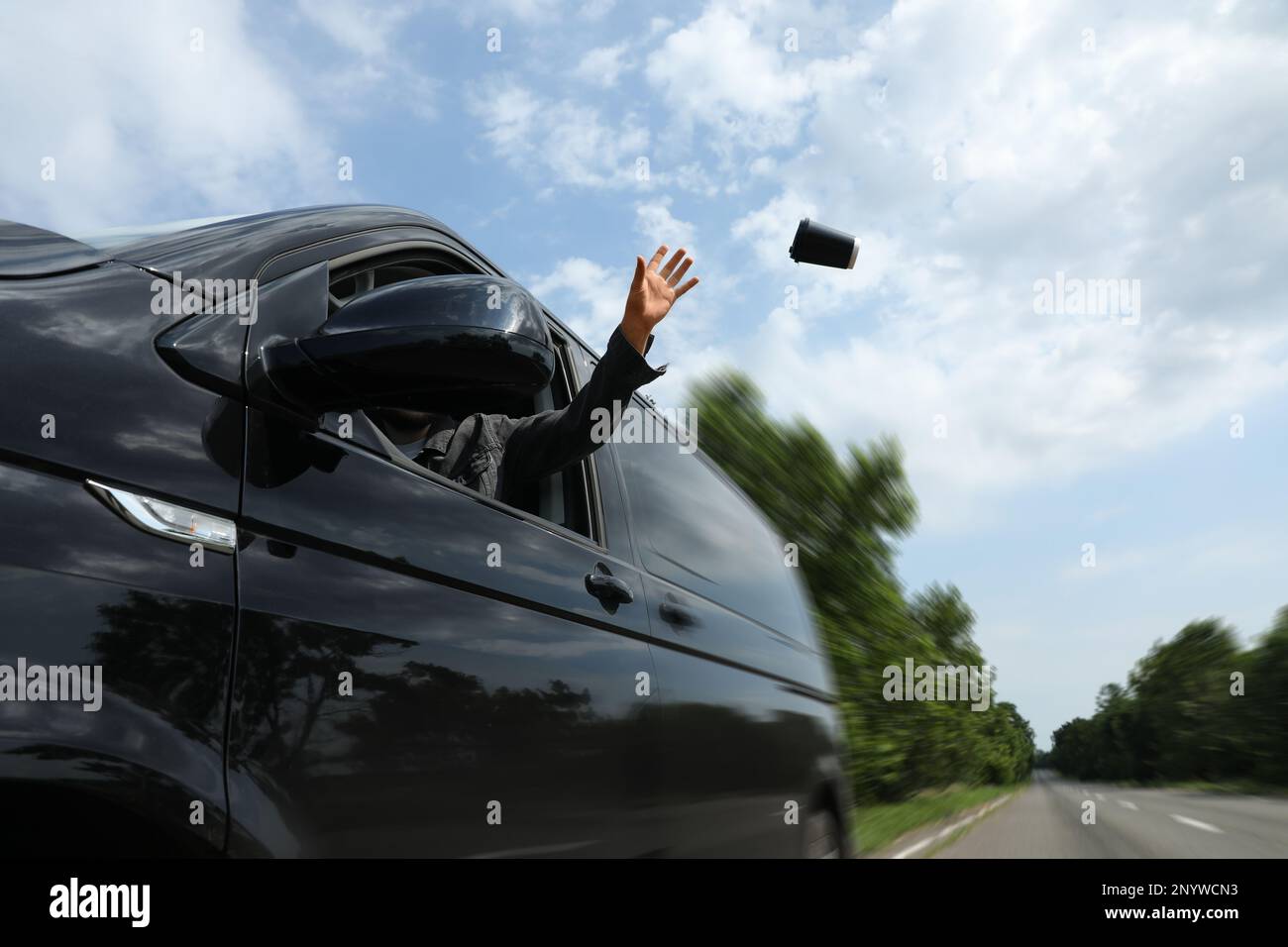 Driver throwing away paper coffee cup from car window, low angle view ...