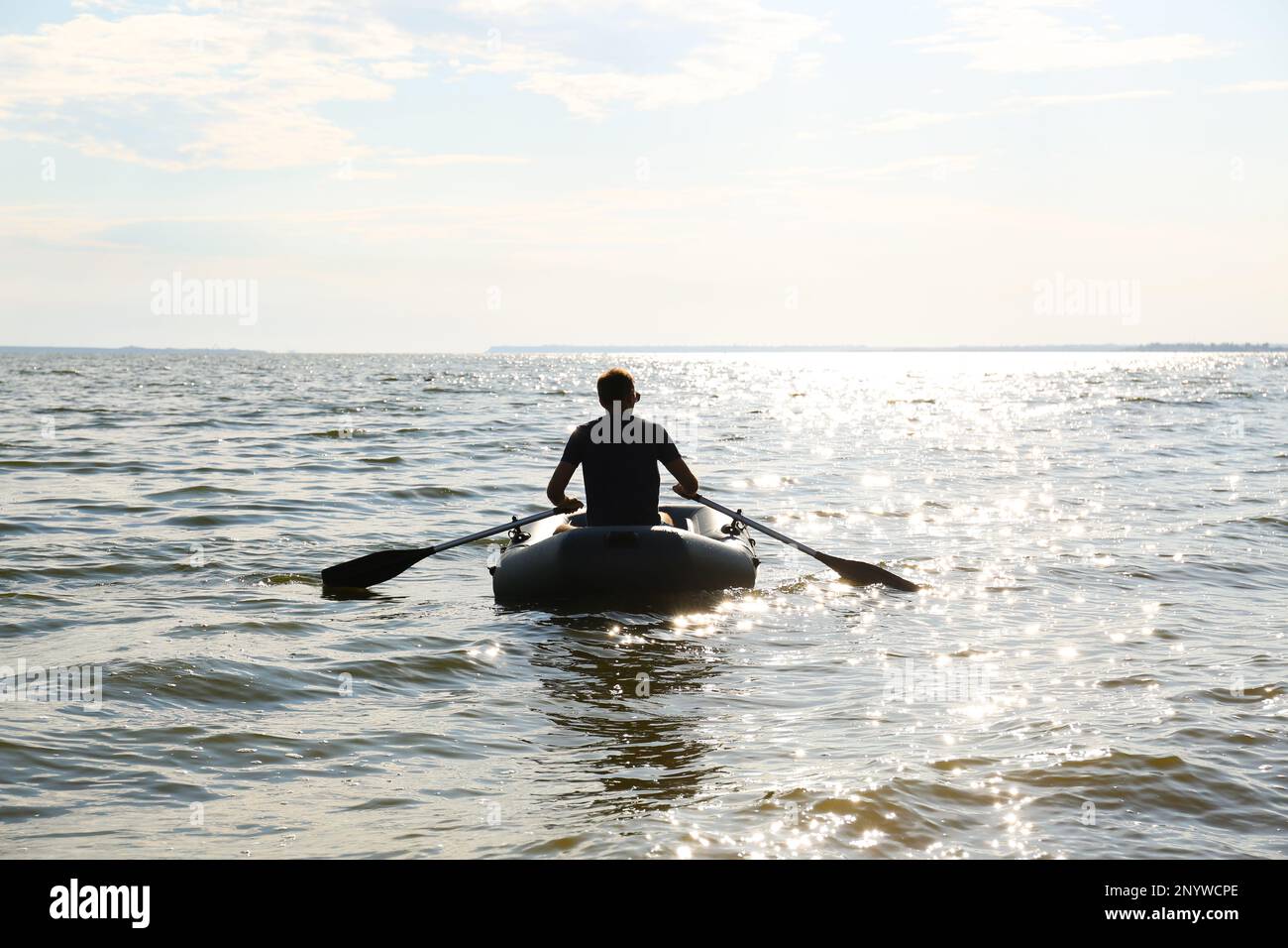 Man rowing inflatable rubber fishing boat on sea, back view Stock Photo ...