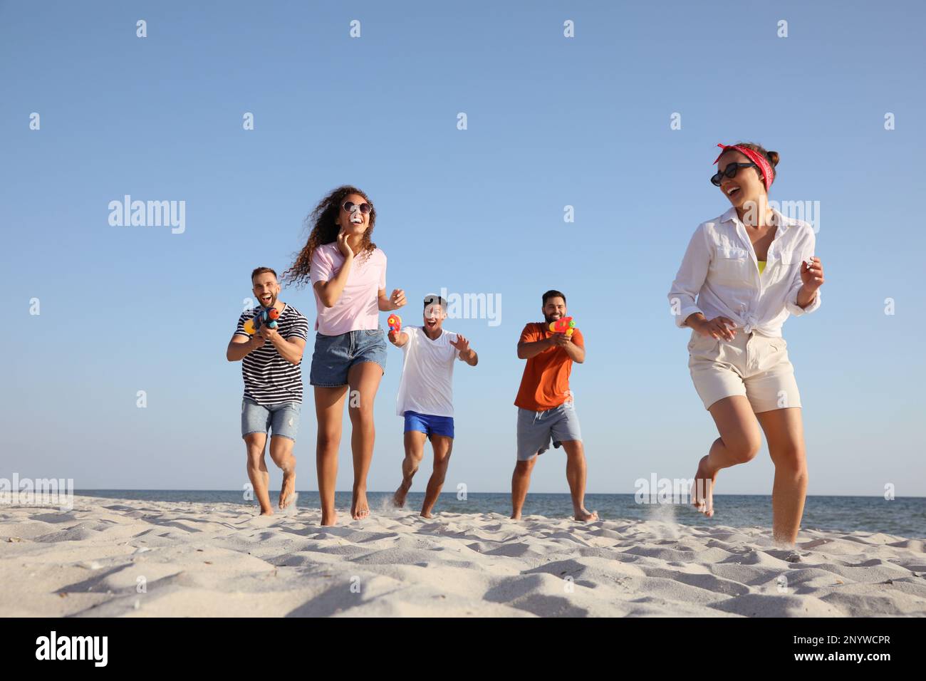 Group of friends with water guns having fun on beach Stock Photo - Alamy
