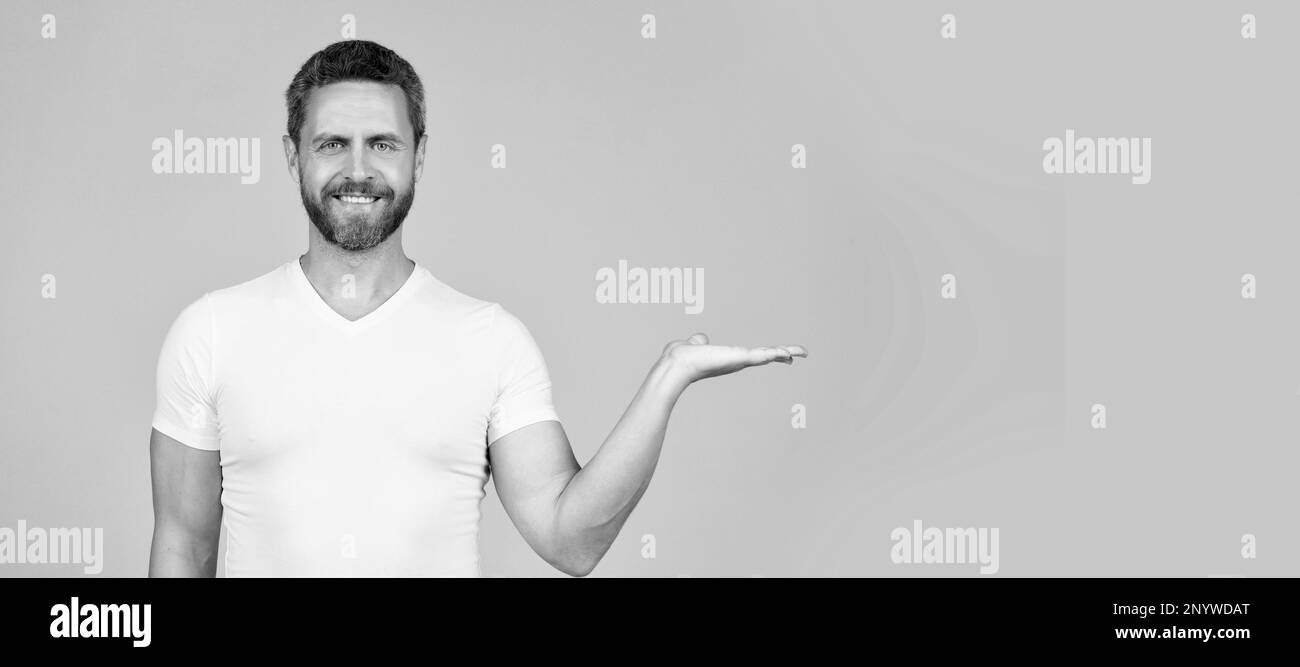 Happy caucasian guy show open hand grey background copy space ...