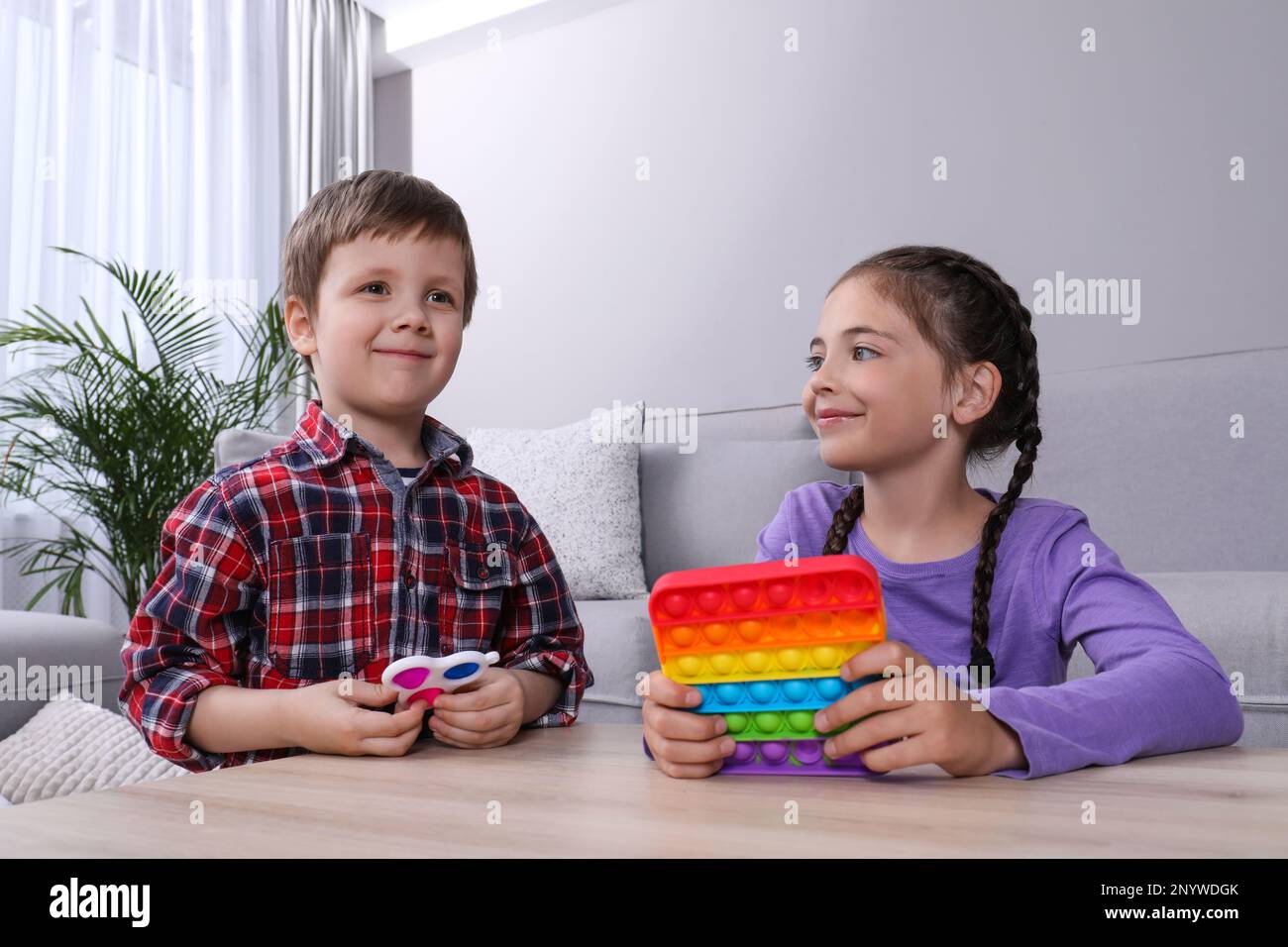 Little children playing with pop it and simple dimple fidget toys at ...