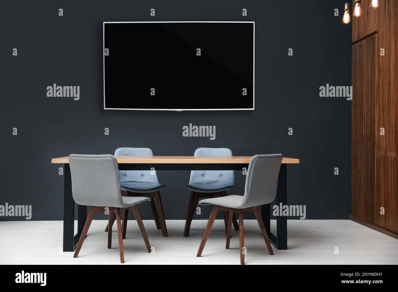 Modern wide screen TV on black wall in room with stylish furniture ...