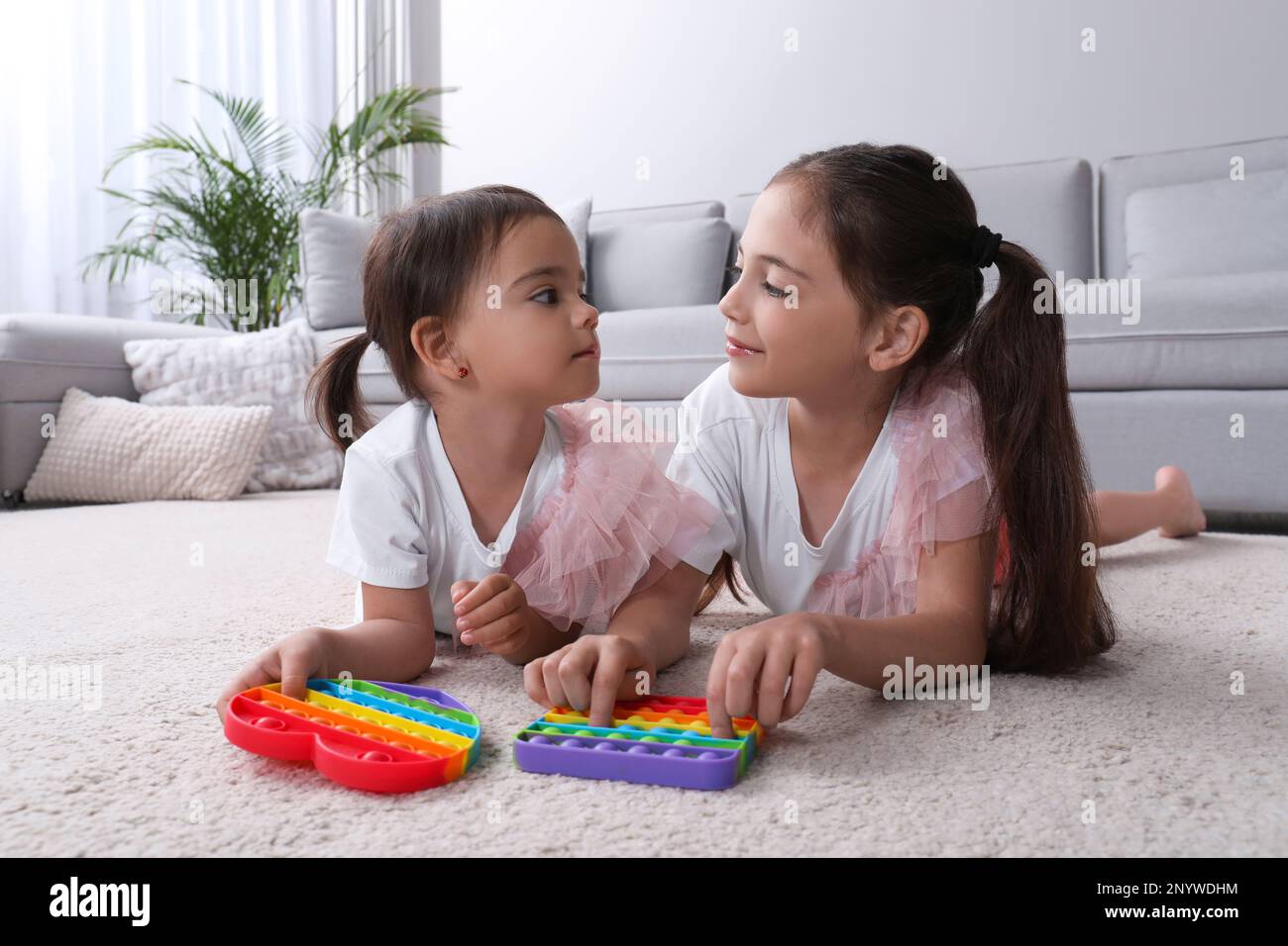 Little girls playing with pop it fidget toys on floor at home Stock ...