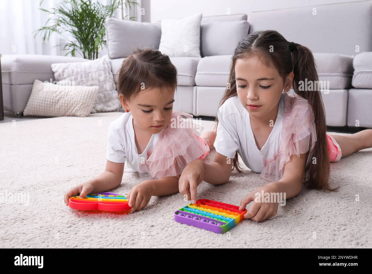 Little girls playing with pop it fidget toys on floor at home Stock ...