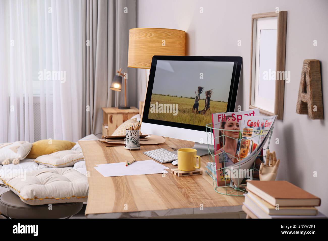 Comfortable workplace with modern computer near light wall in bedroom ...