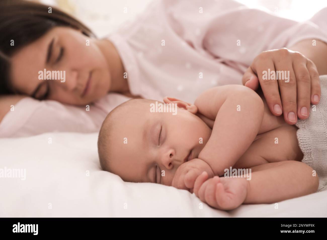 Young mother resting near her sleeping baby on bed at home Stock Photo ...