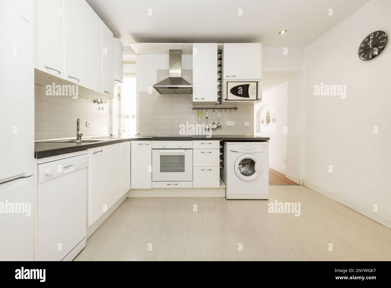 L-shaped kitchen with smooth white wood furniture with integrated ...