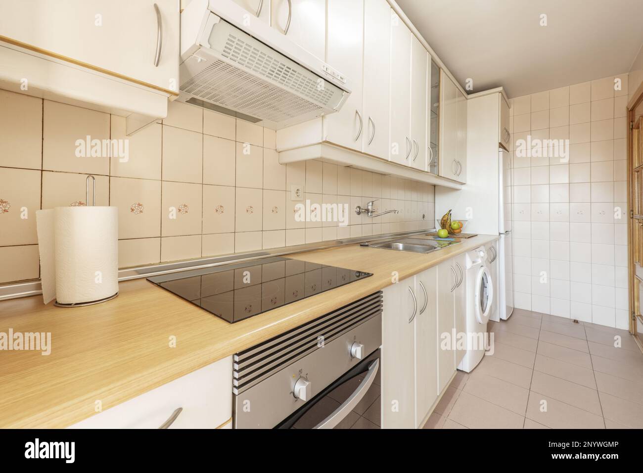 Kitchen with a wall covered in white cabinets with a wooden countertop ...