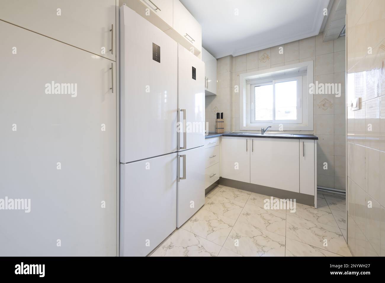 Kitchen furnished with smooth and shiny white cabinets with stainless ...