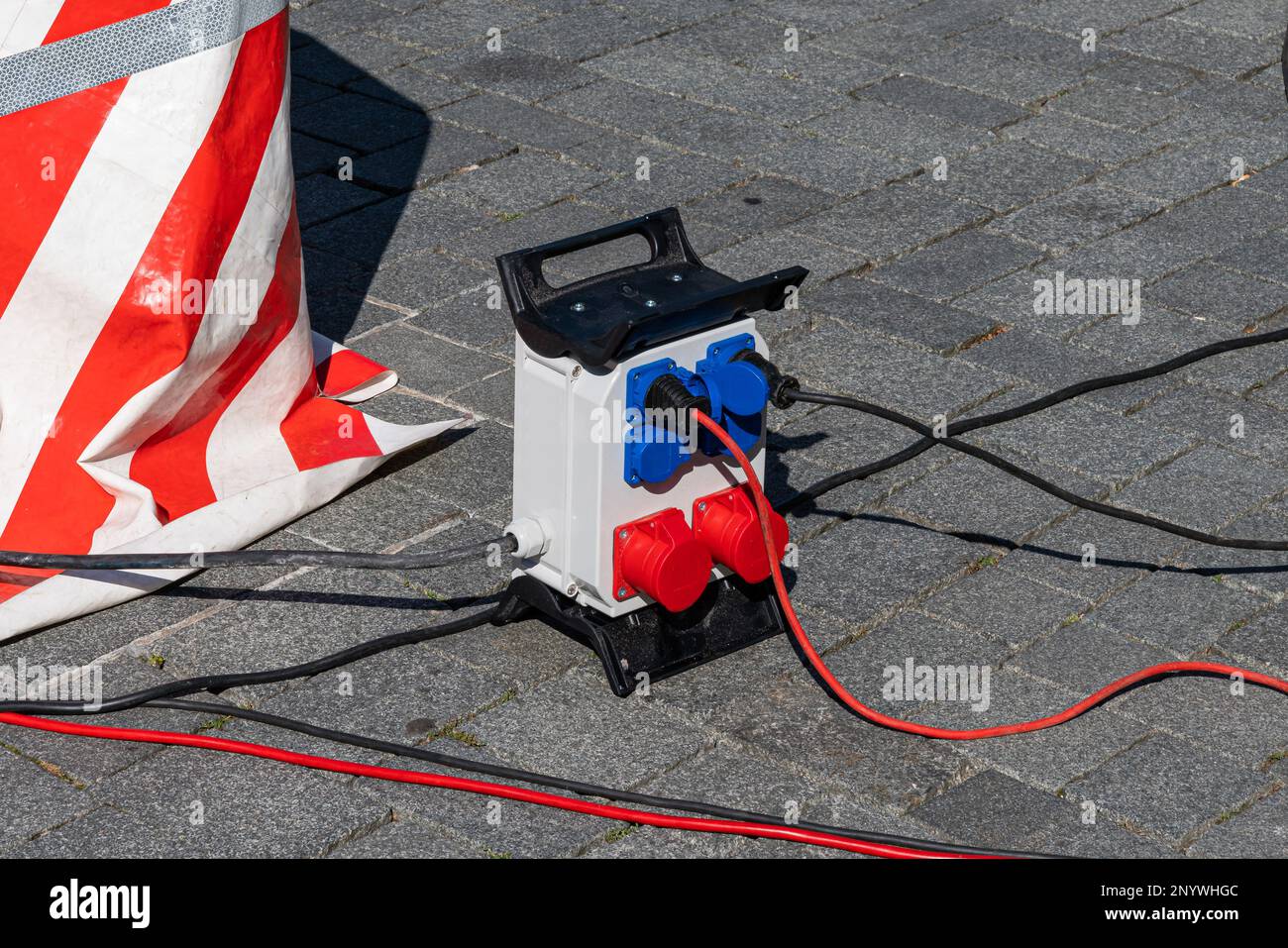 Portable electricity distributor on a paved street. Black and red ...