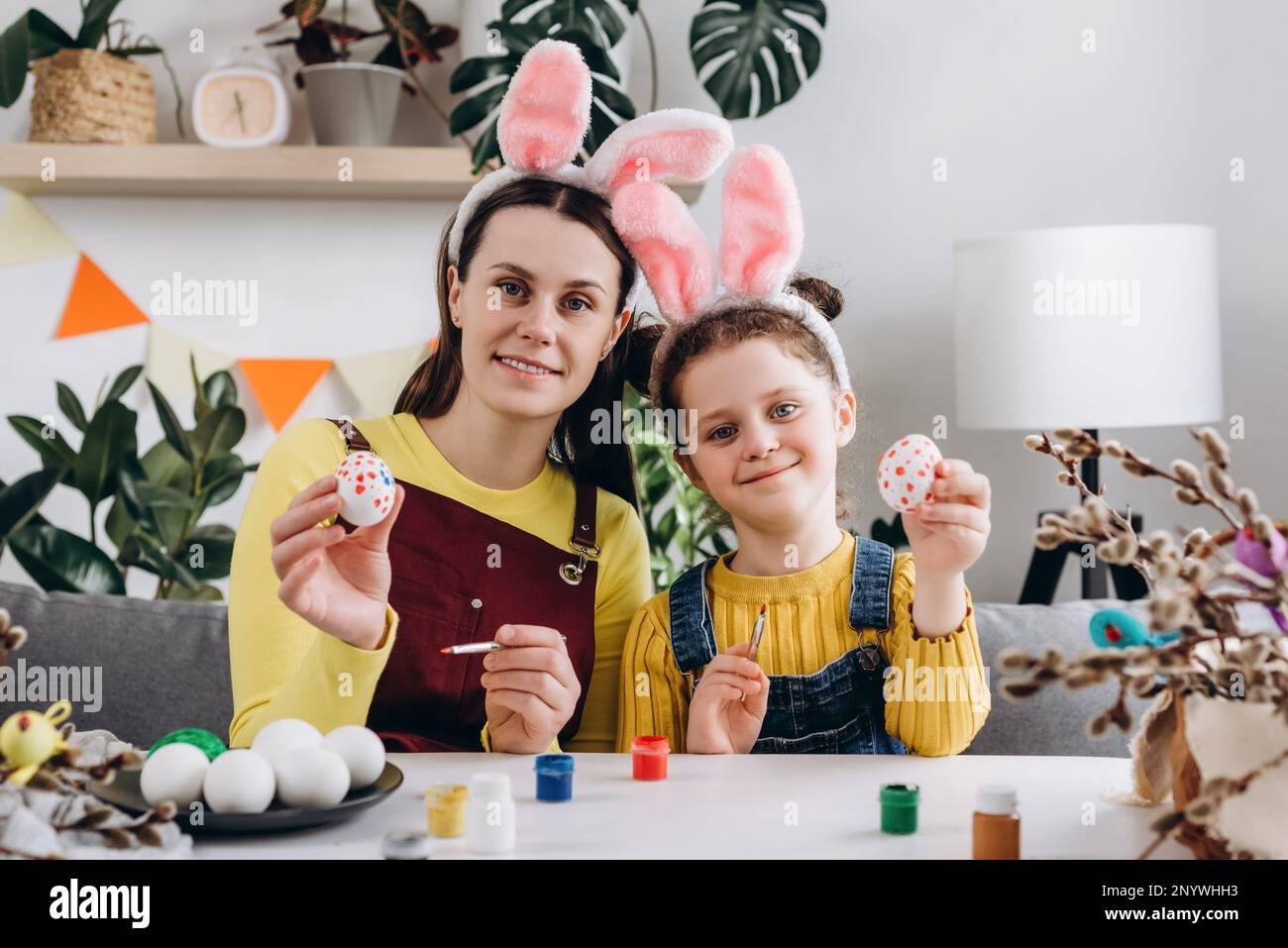 Portrait of smiling young mom and sweet daughter celebrating easter ...