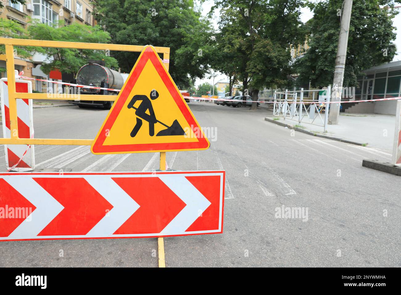 Barricade with road construction sign on city street, space for text ...