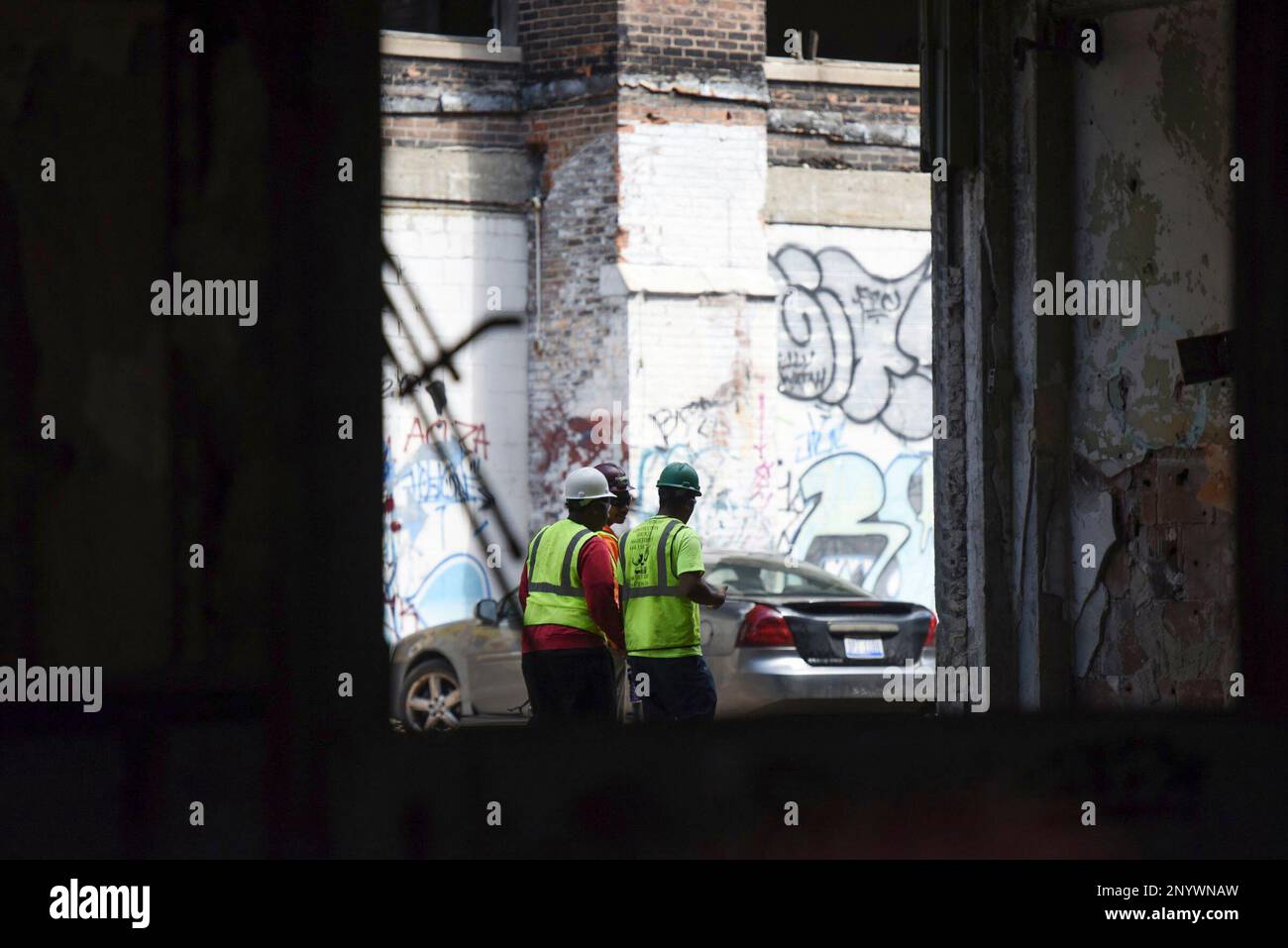 Workers in yellow vests walk through the long-vacant Packard auto plant ...