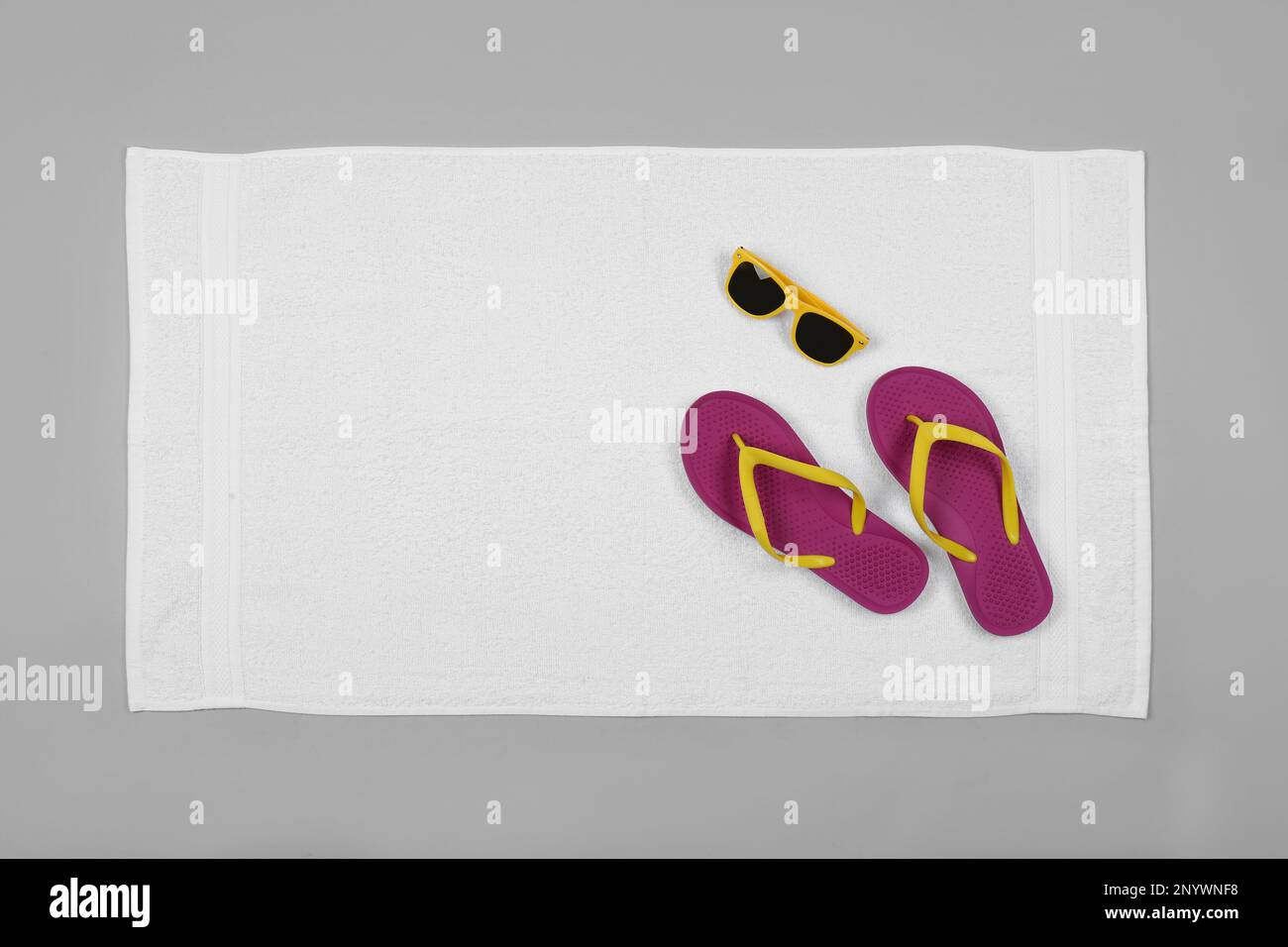 White beach towel with flip flops and sunglasses on light grey ...