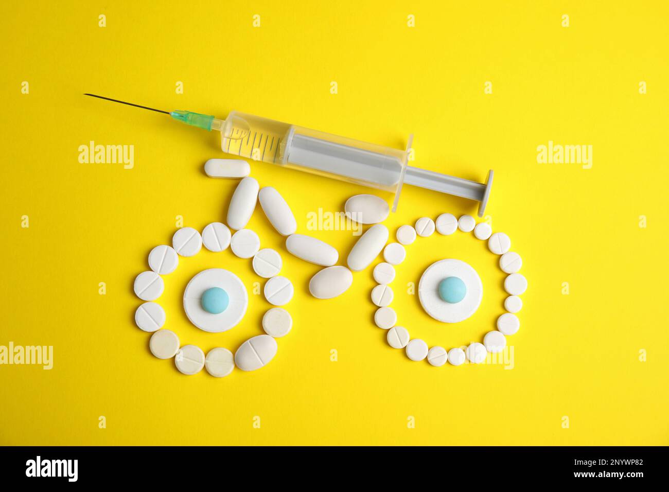 Bike made of pills and syringe on yellow background, flat lay. Using ...