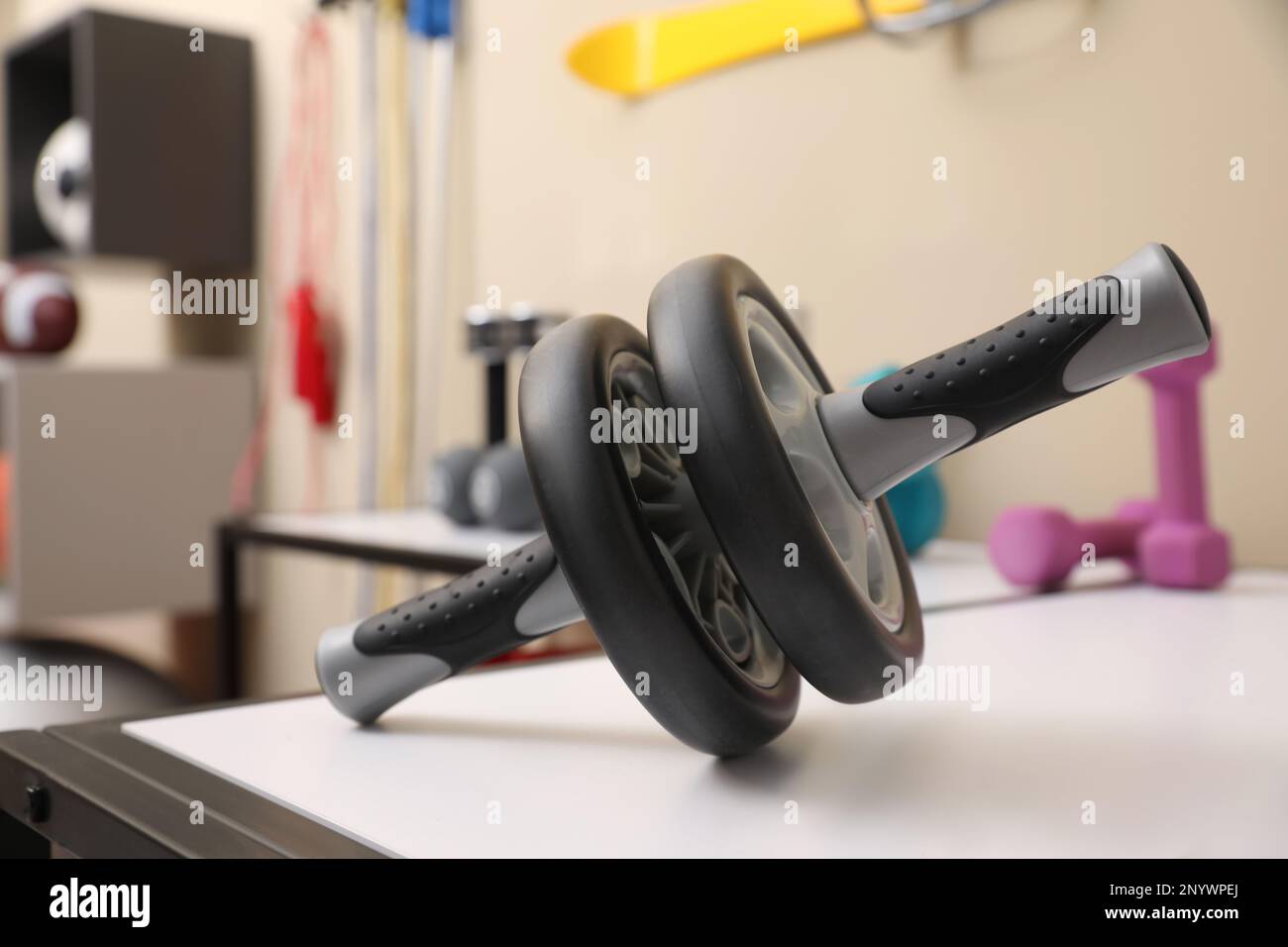 Abdominal wheel on white table in room with other sports equipment ...