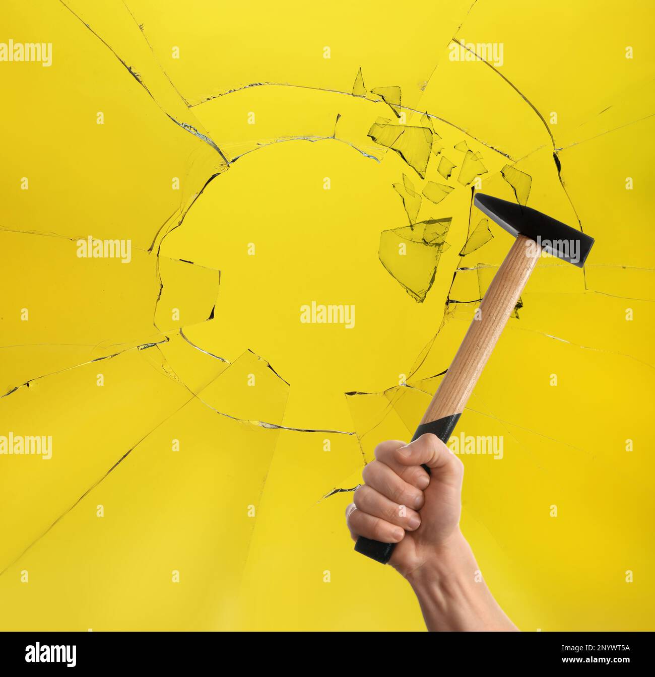 Man with hammer breaking up glass against yellow background. closeup ...