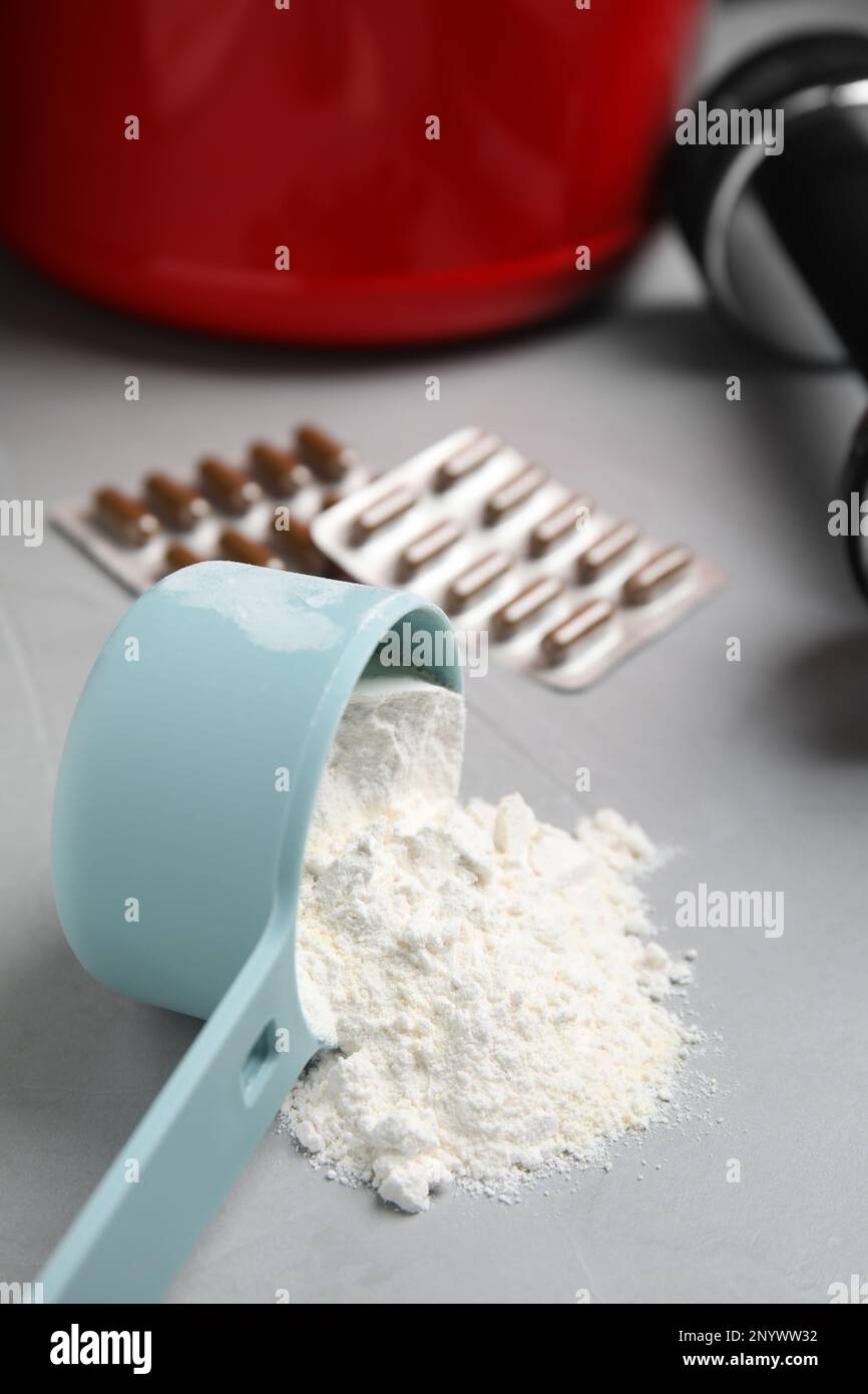 Measuring scoop of amino acids powder on light grey table Stock Photo ...