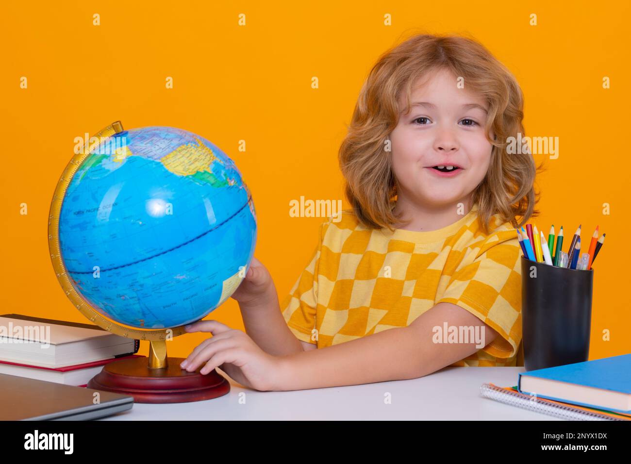 Little student school child looking at globe during geography lesson ...