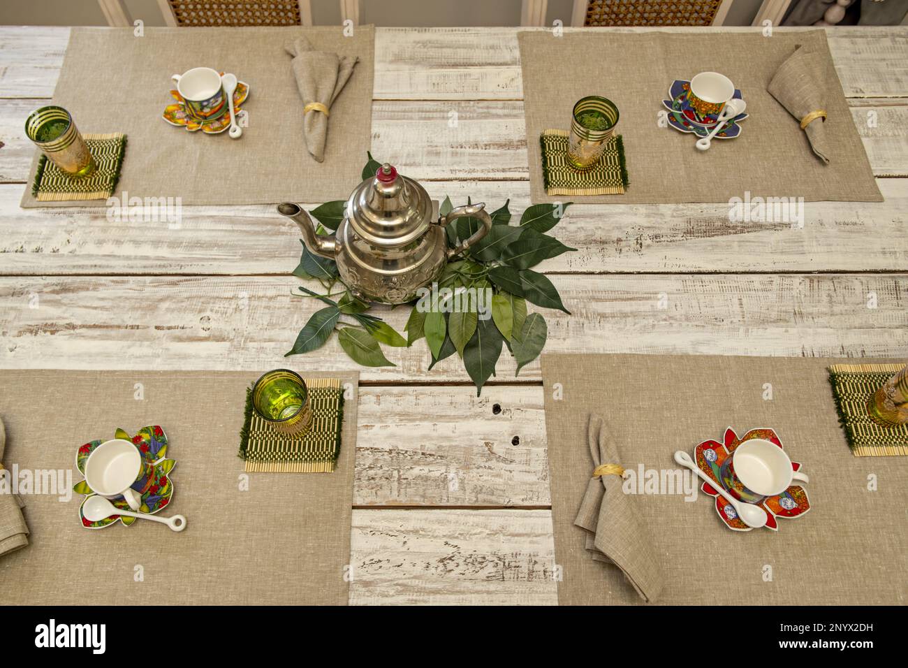 A white wooden dining table with small white porcelain teacups and ...