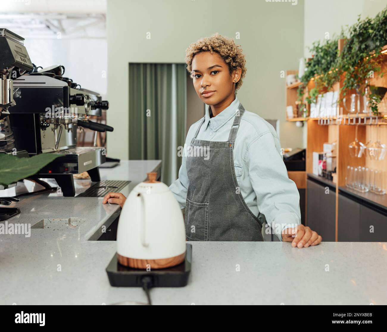 Young barista in a coffee shop. Young female with short hair working as ...