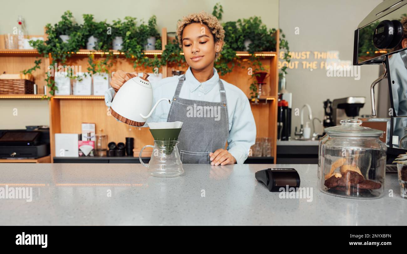 Woman barista pouring water from kettle to a filter at counter Stock ...