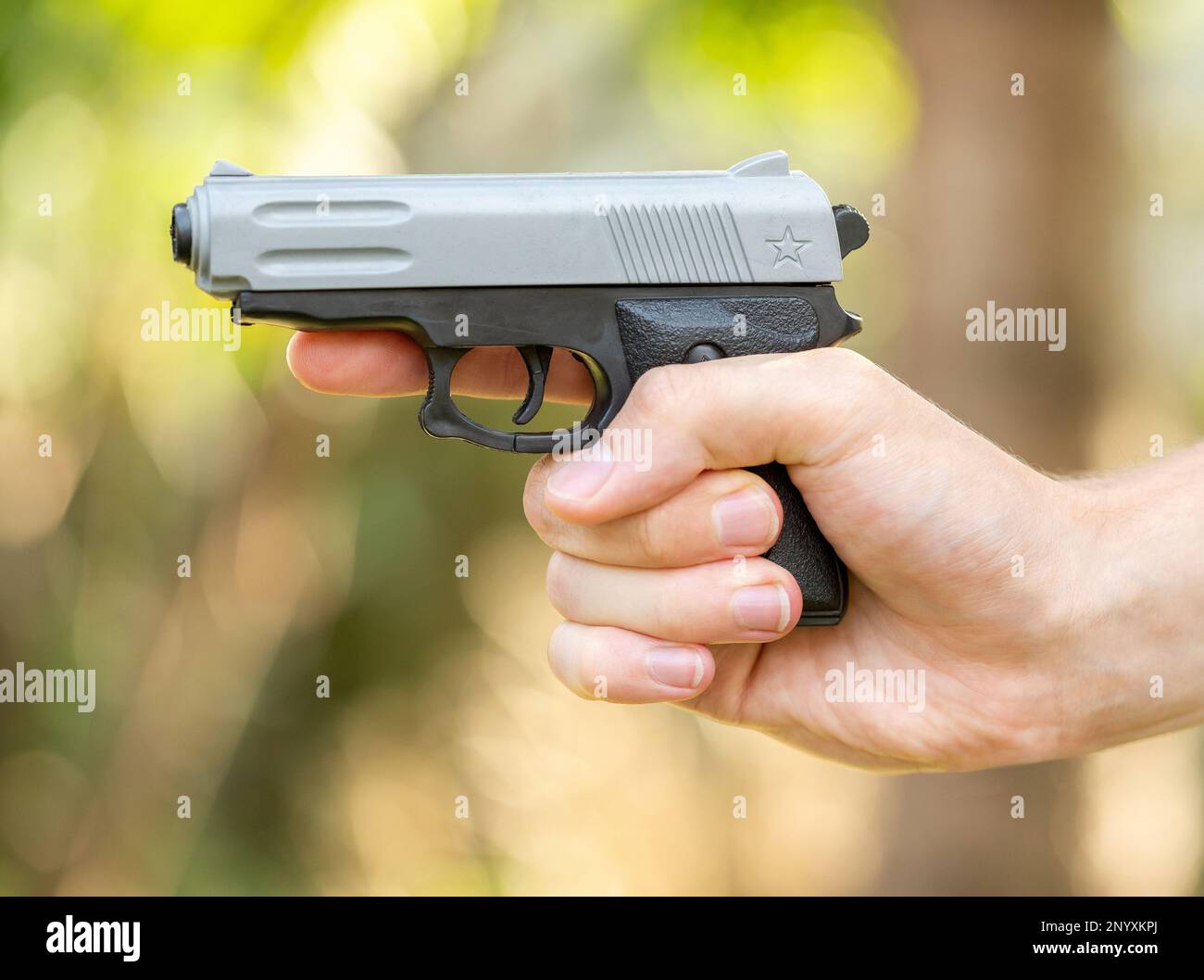 Hand holding a simple small generic plastic toy gun, pistol, fake ...