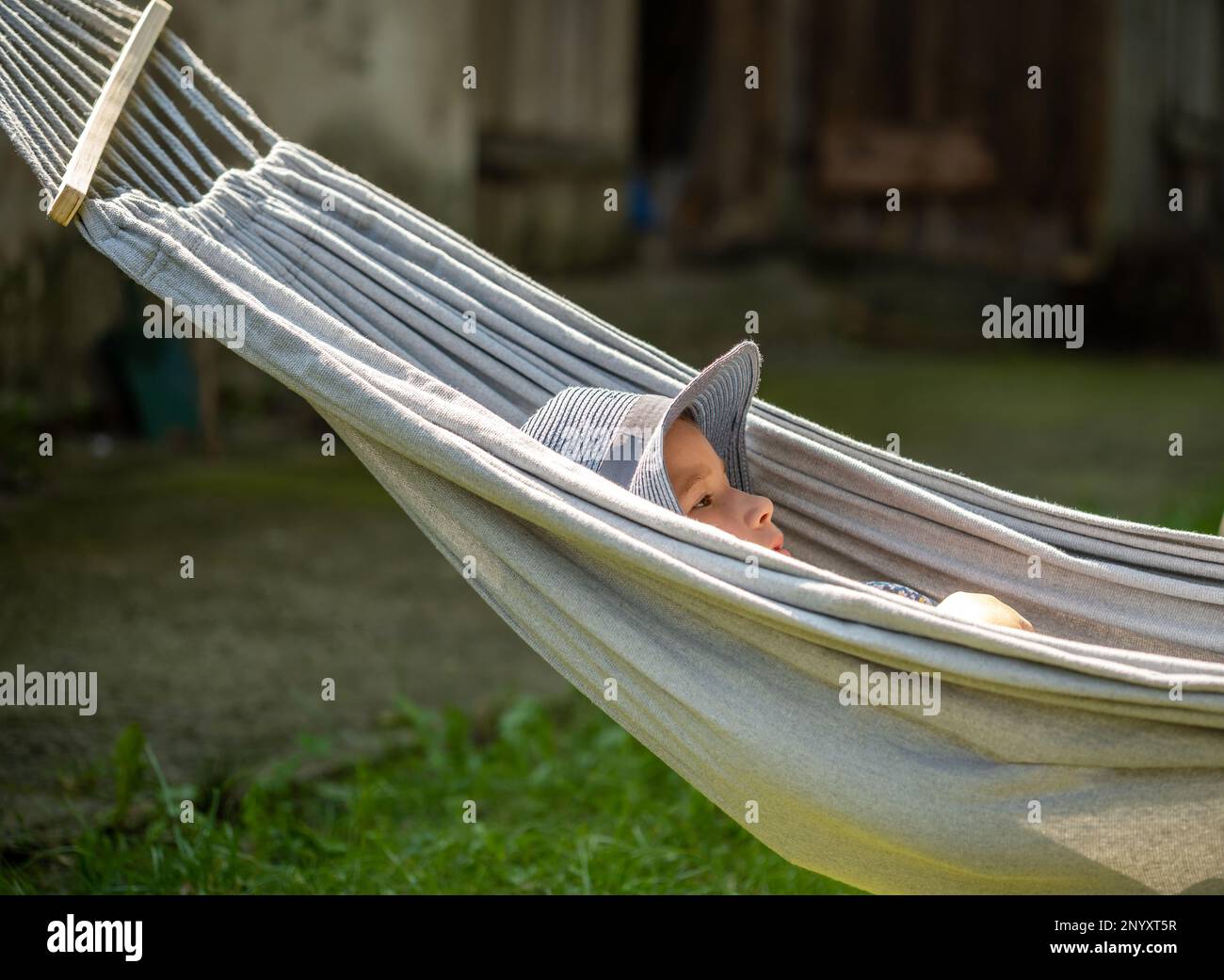 Child, elementary school age girl lying in a hammock outdoors, resting ...